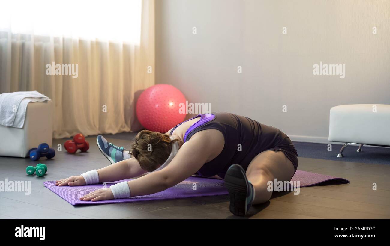Motivated girl doing exercises with pleasure, stretching back and legs ...