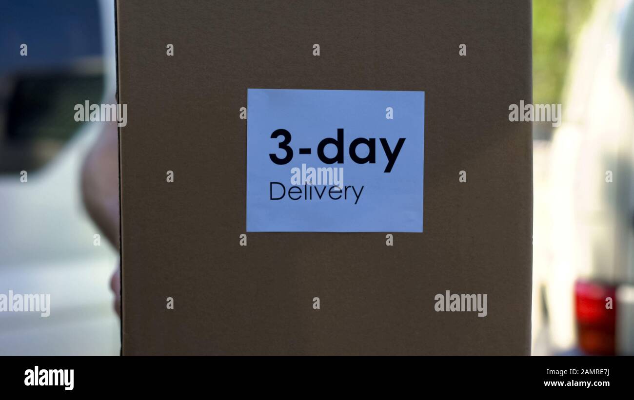 Three day delivery courier in uniform holding cardboard box, quality ...