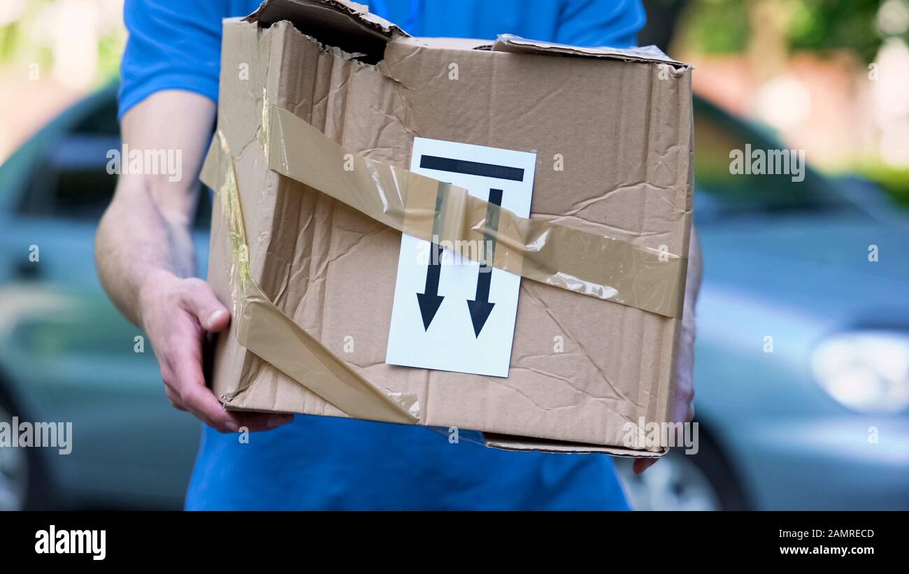 Frightened delivery worker giving broken customer parcel, shipment ...