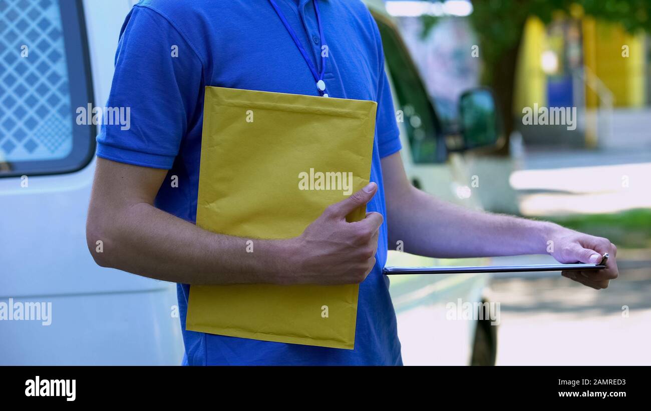 Courier holding yellow package and proof delivery form, documents ...