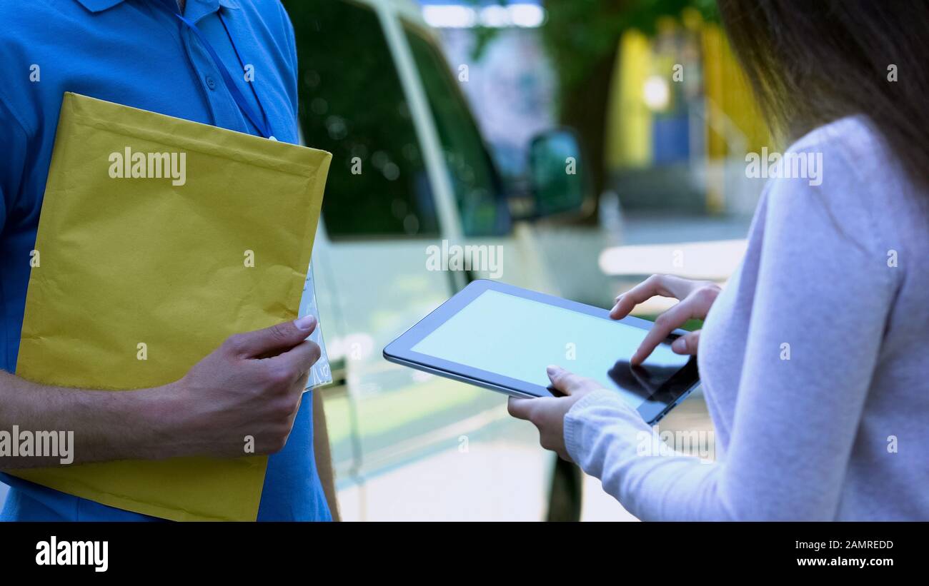 Female signing for parcel receiving in tablet app, delivery company ...