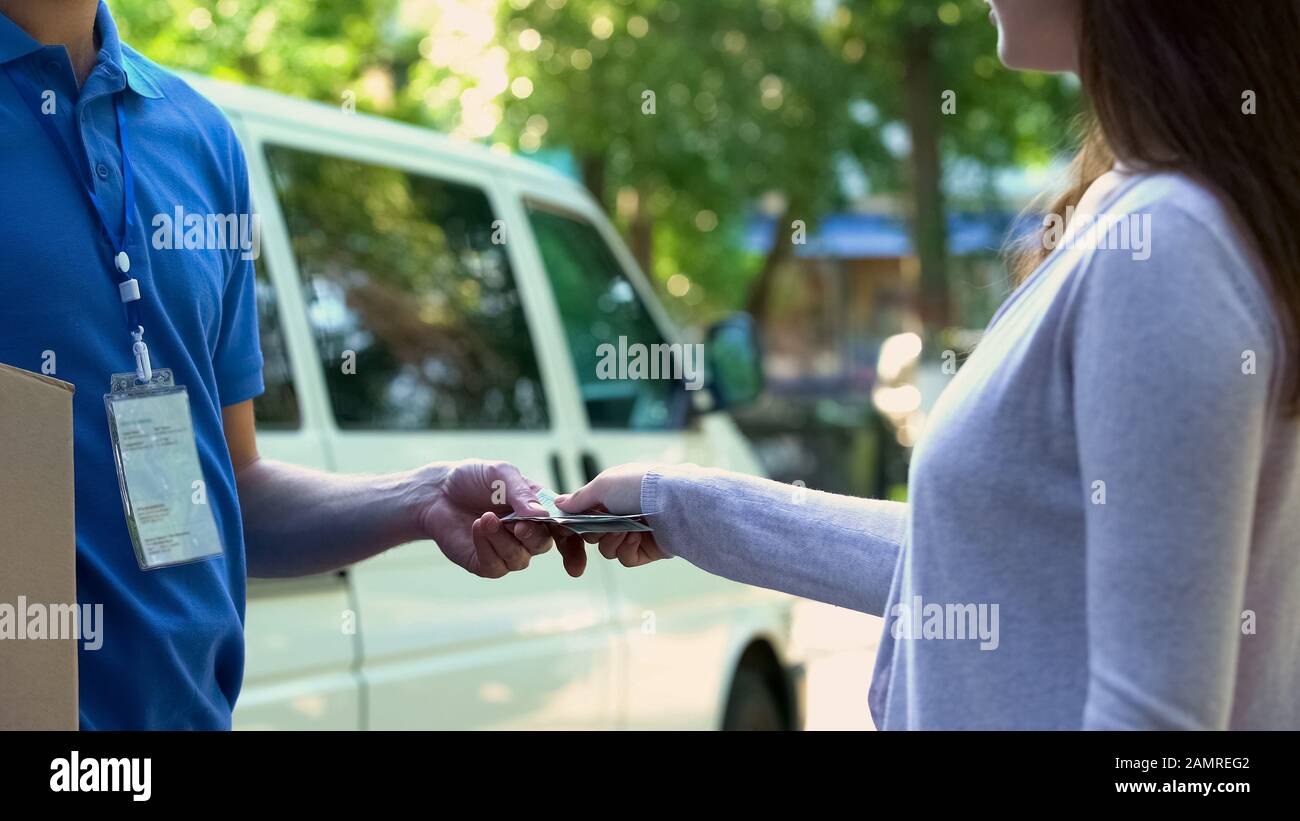 Courier receiving cash payment for cardboard parcel delivery, express ...
