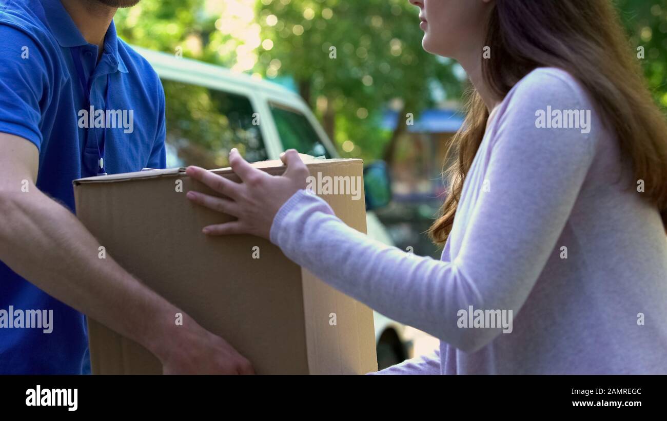 Female client receiving cardboard parcel from delivery service, express ...