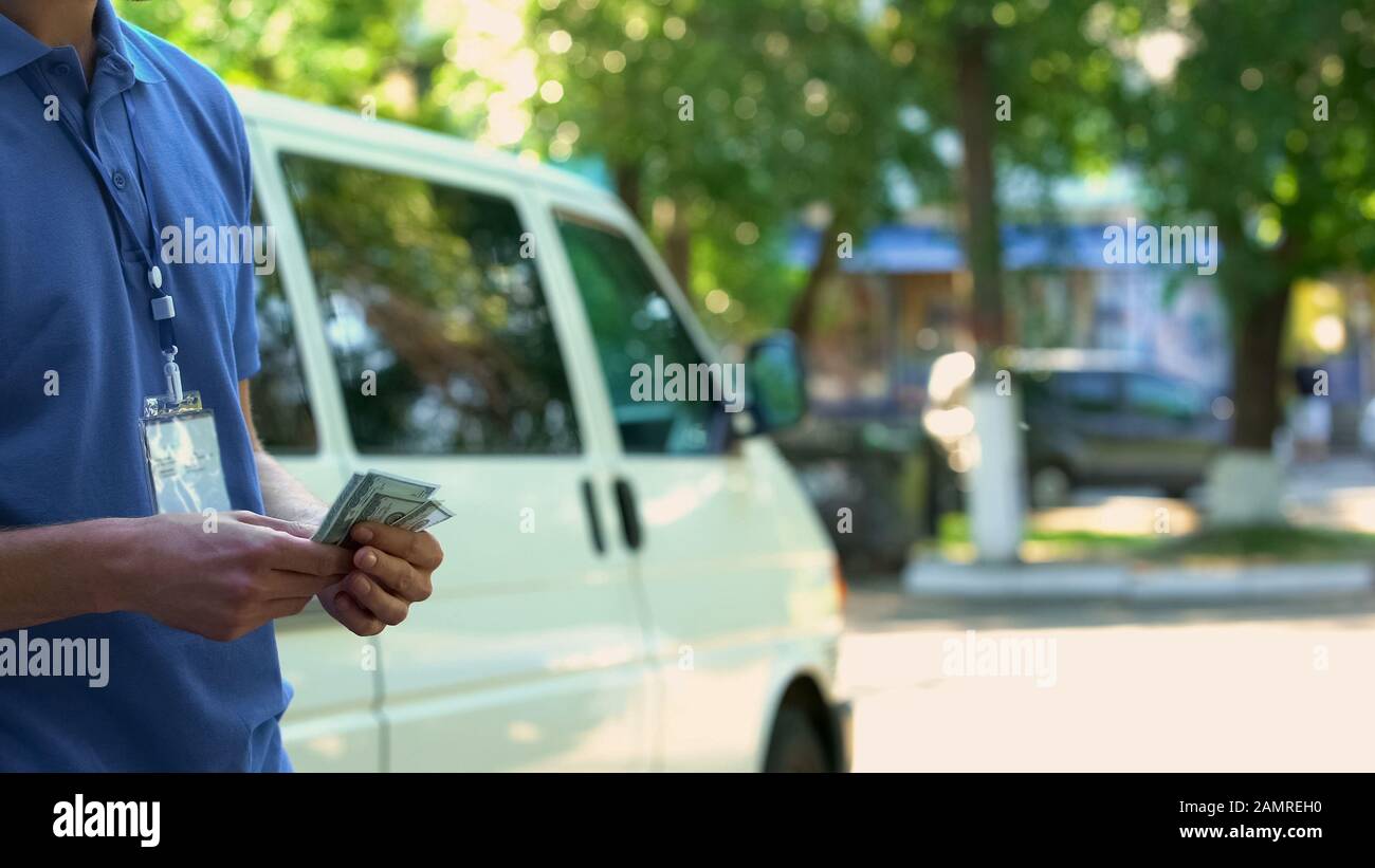 Male courier counting money received for parcel delivery, hourly ...