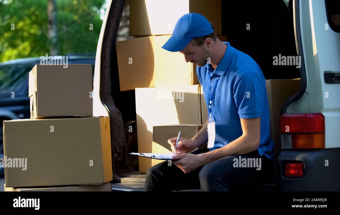 Worker of post office counting cardboard boxes filling inventory report ...