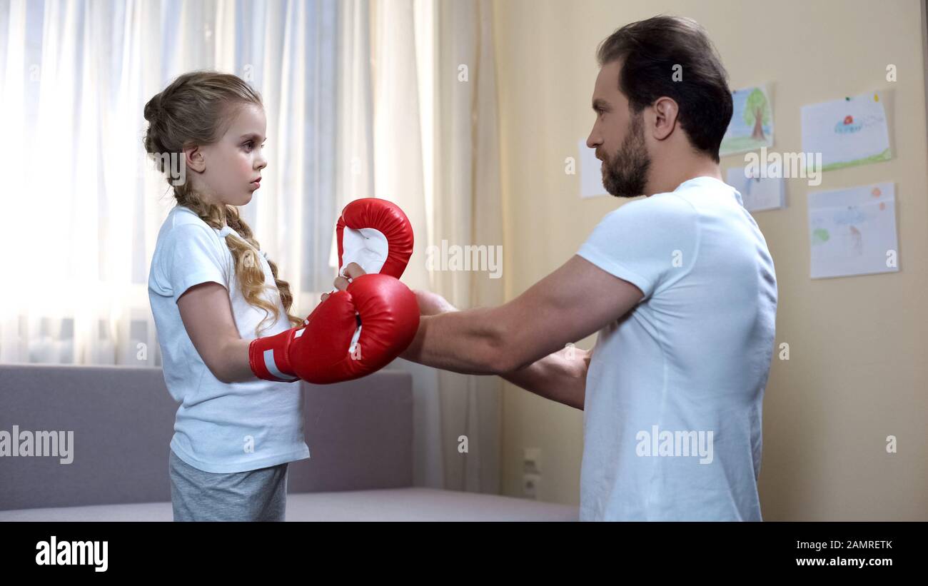 Caring father helping child put on boxing gloves, sport childhood ...