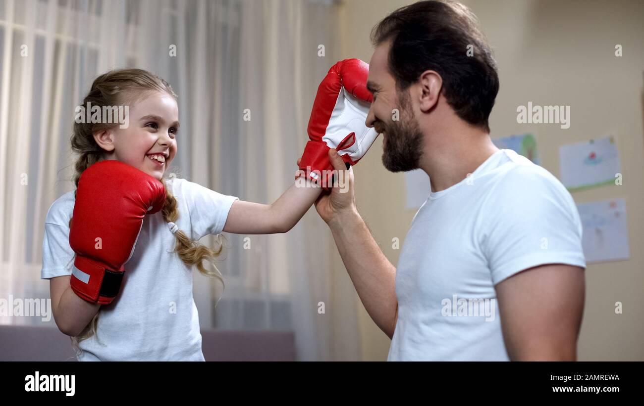 Happy daughter boxing with bearded father at home, sport childhood and ...