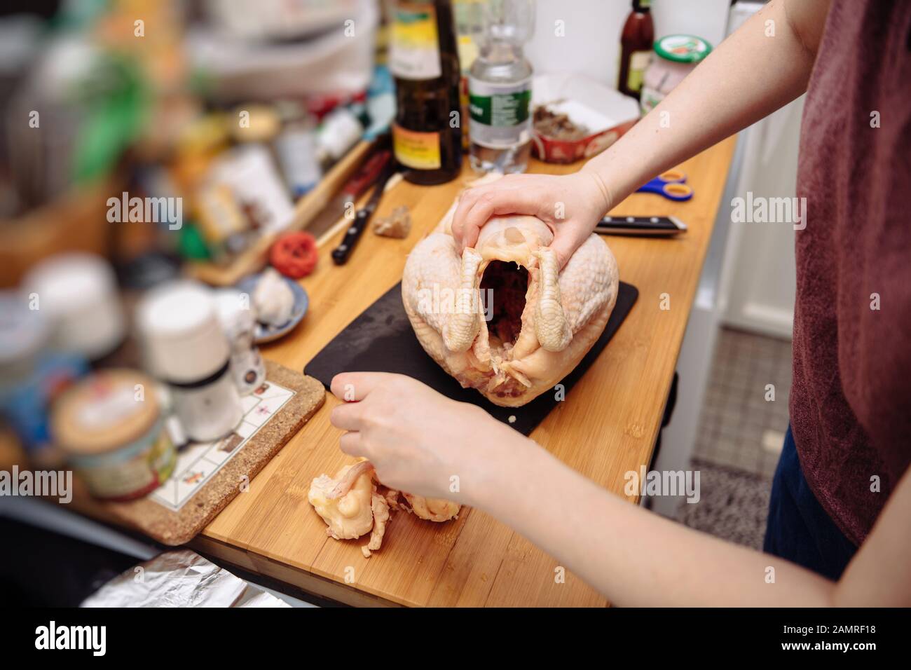 Woman removing fat from fresh Capon Chapon cockerel meat on kitchen ...