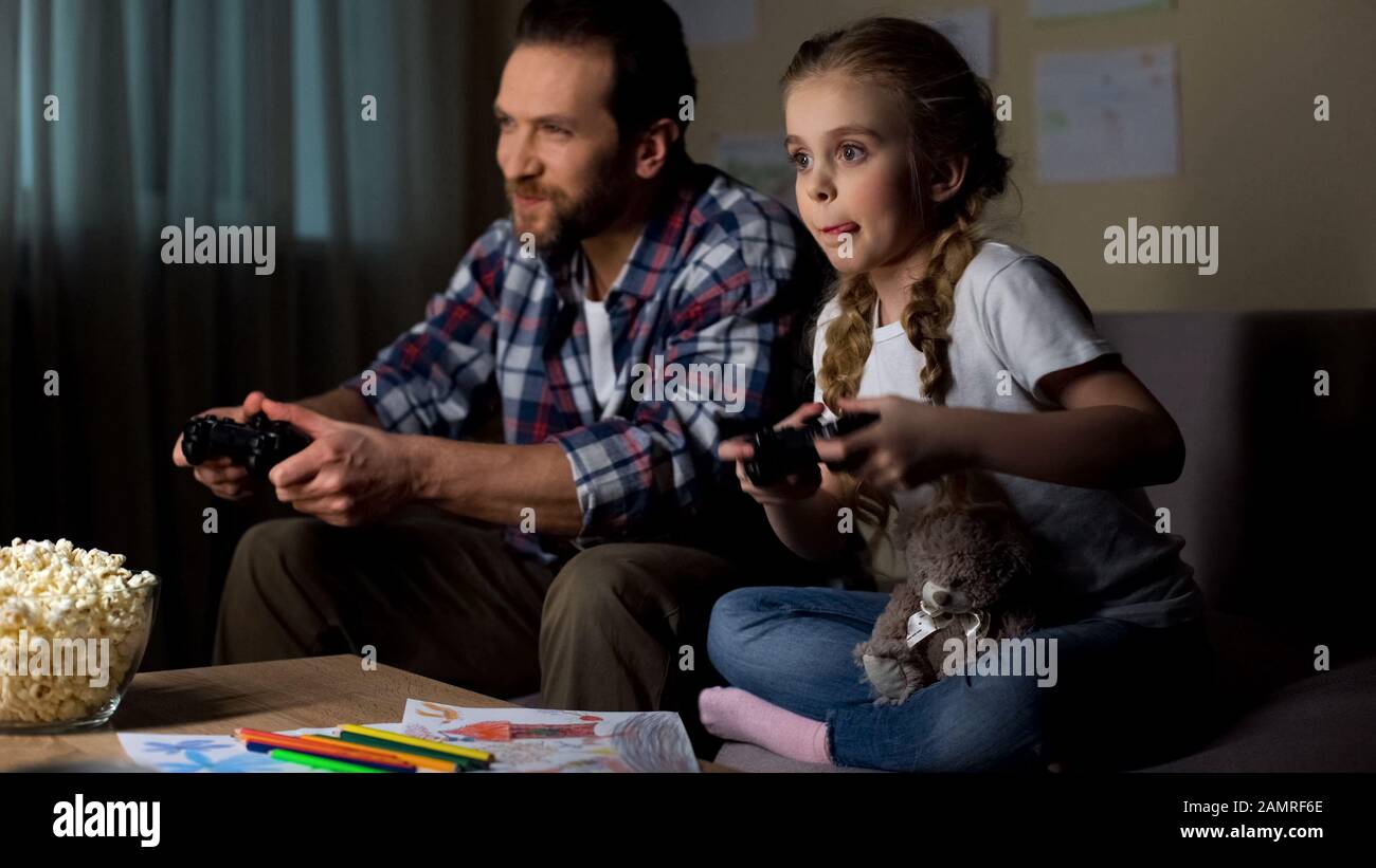 Dad and little child playing video game with joysticks together home ...