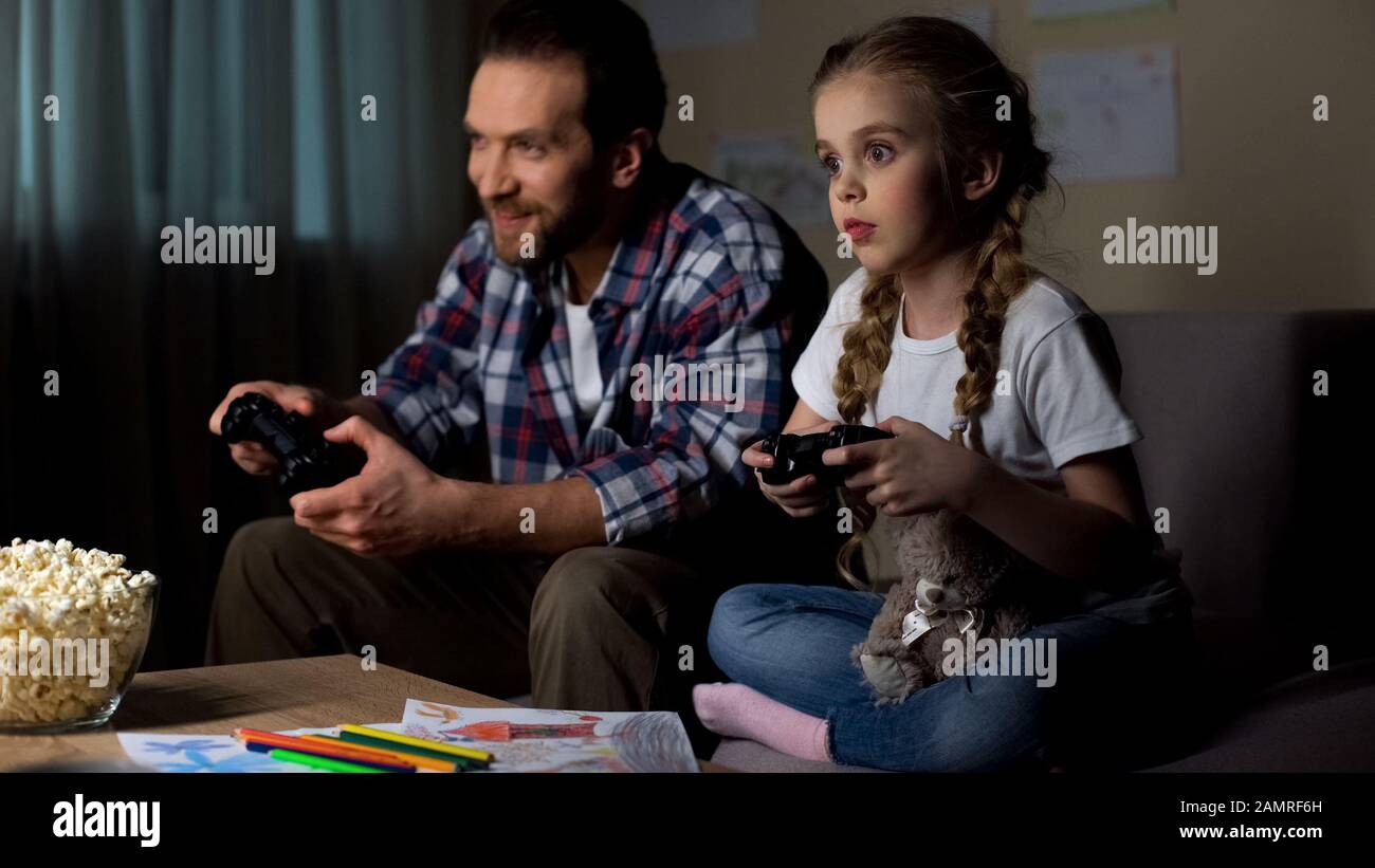 Father and cute kid playing video game with joysticks together home ...