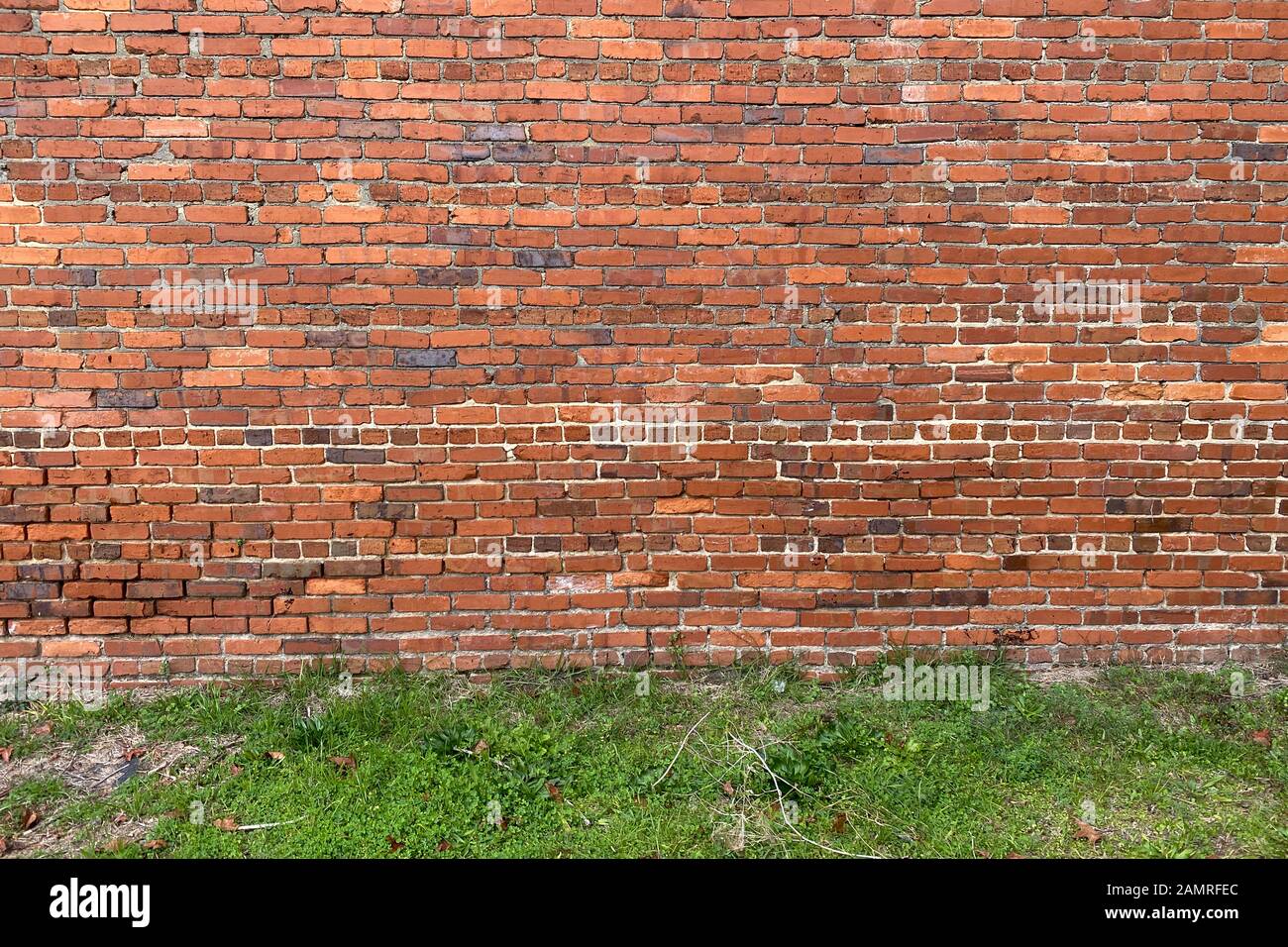red brick wall in an alley and grass path Stock Photo - Alamy