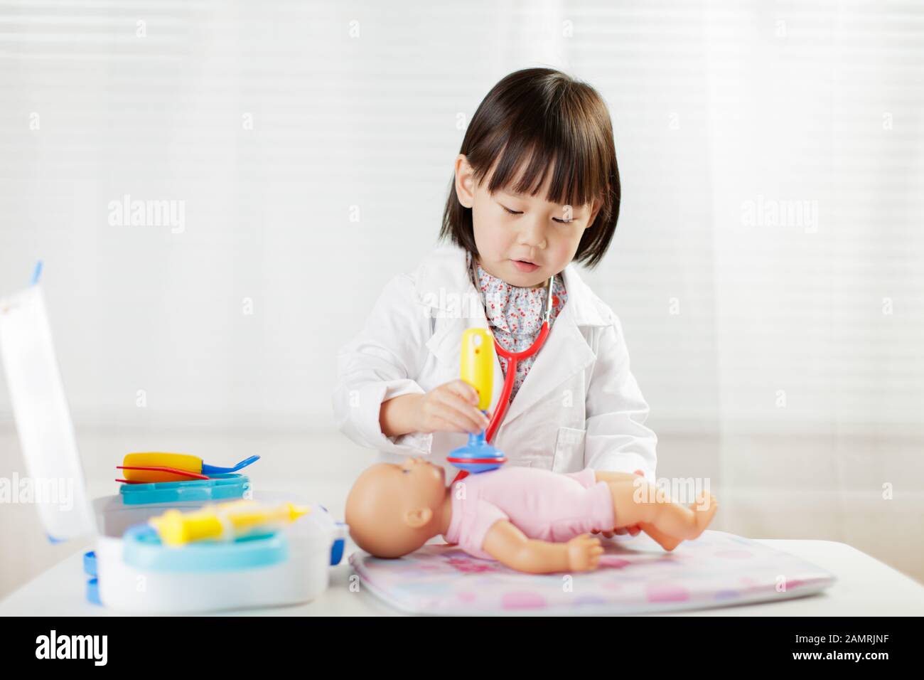 toddler girl pretend play doctor role at home against white background ...