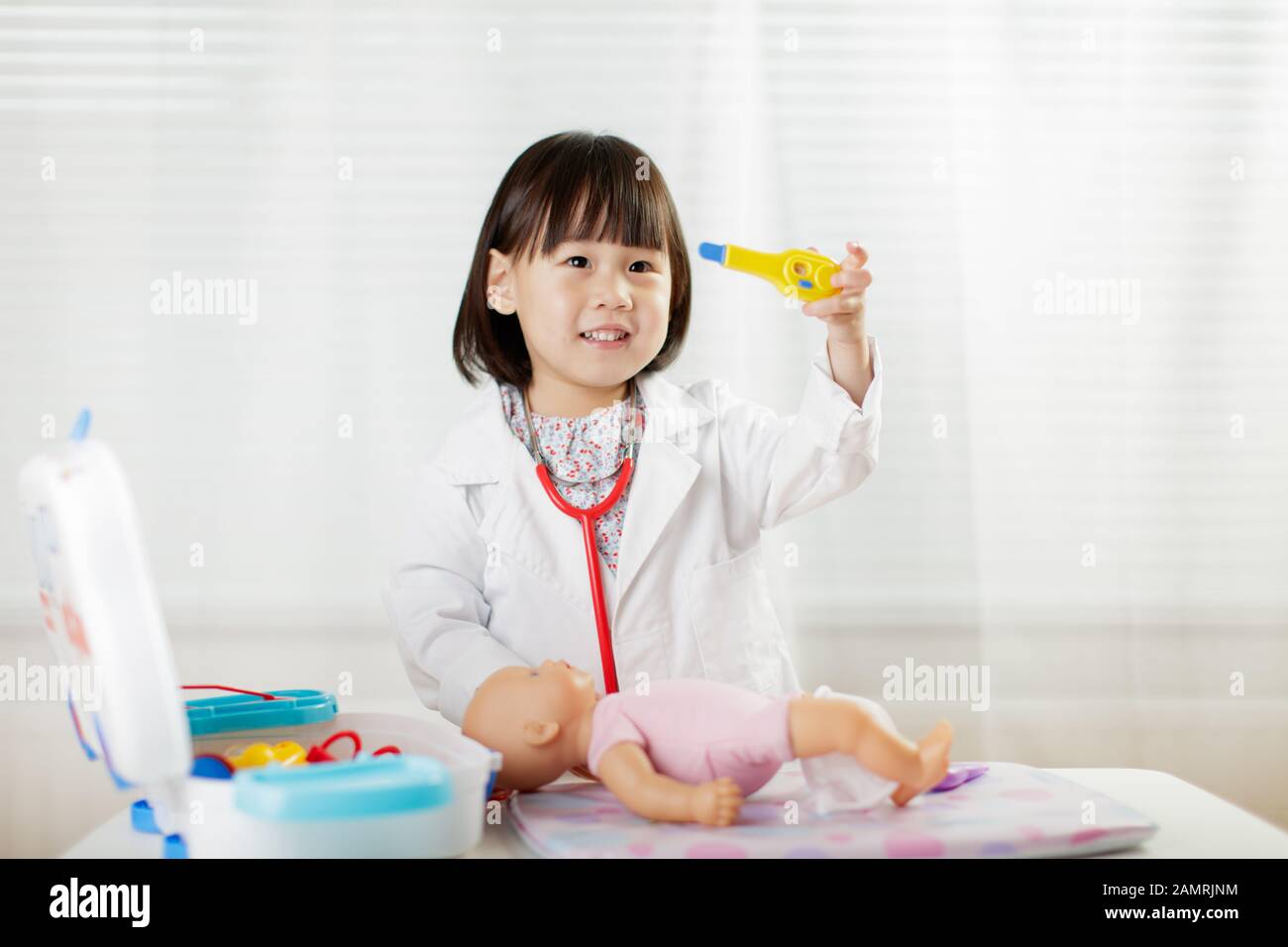 toddler girl pretend play doctor role at home against white background ...