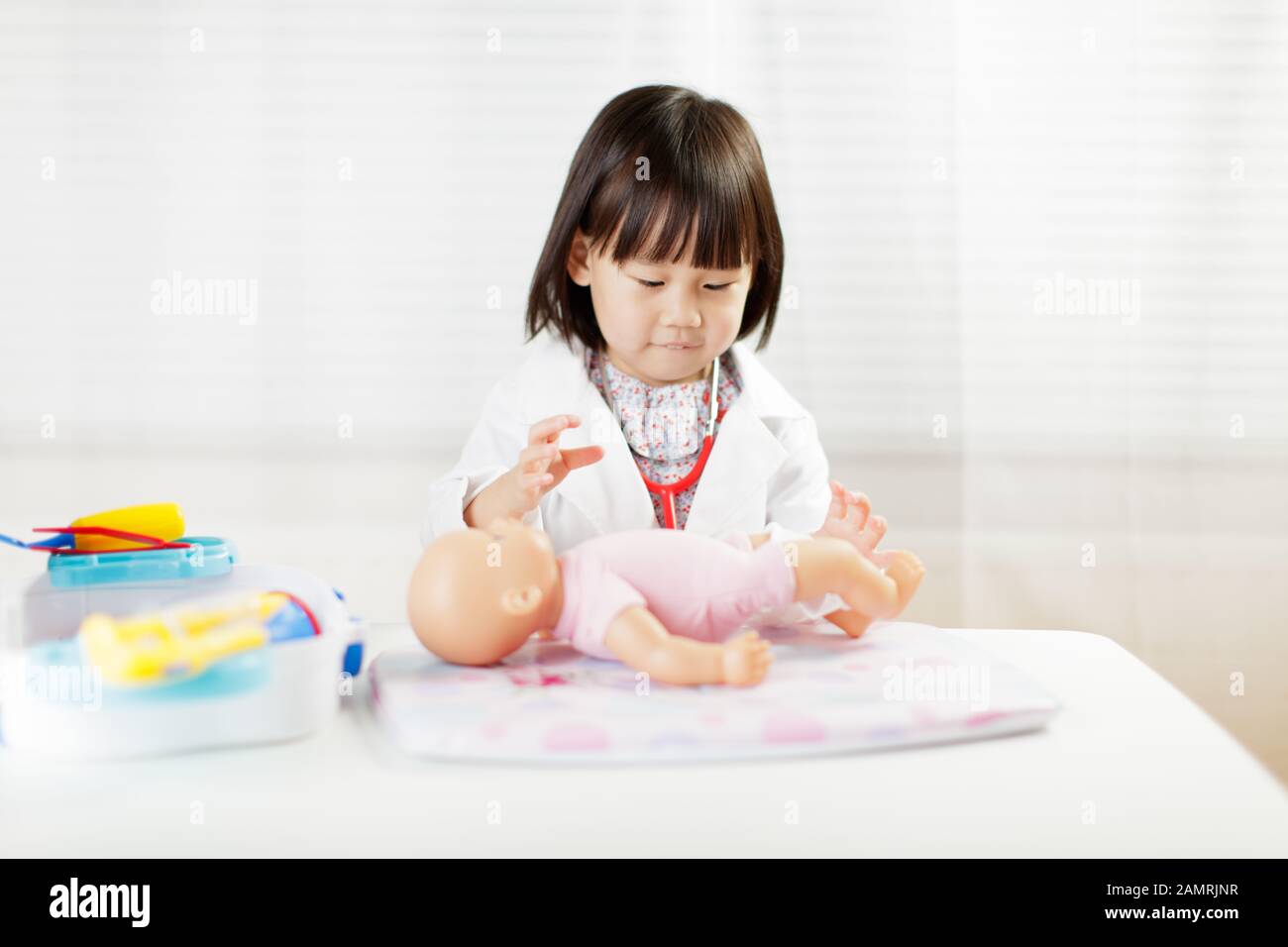 toddler girl pretend play doctor role at home against white background ...