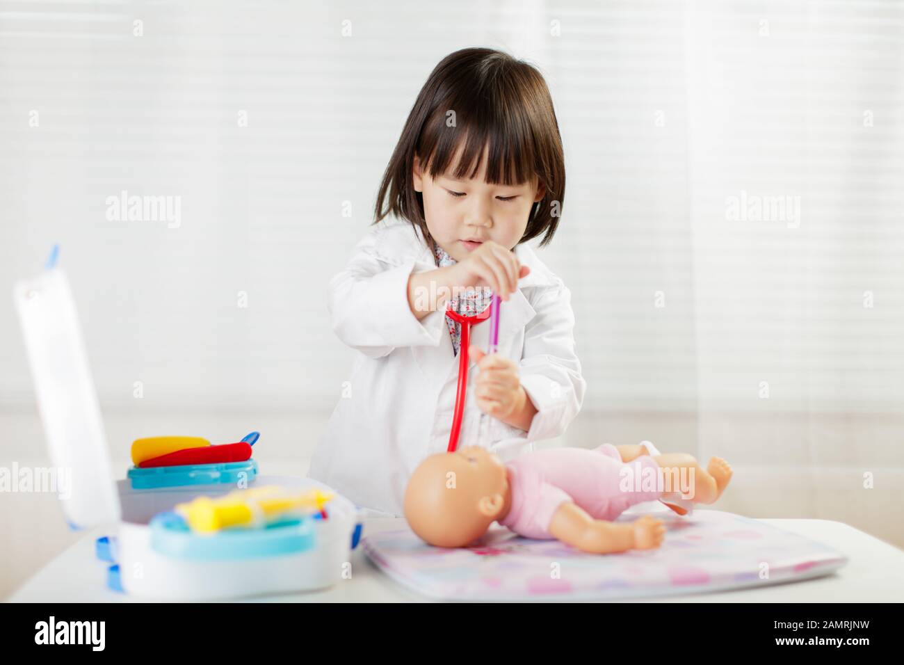 toddler girl pretend play doctor role at home against white background ...