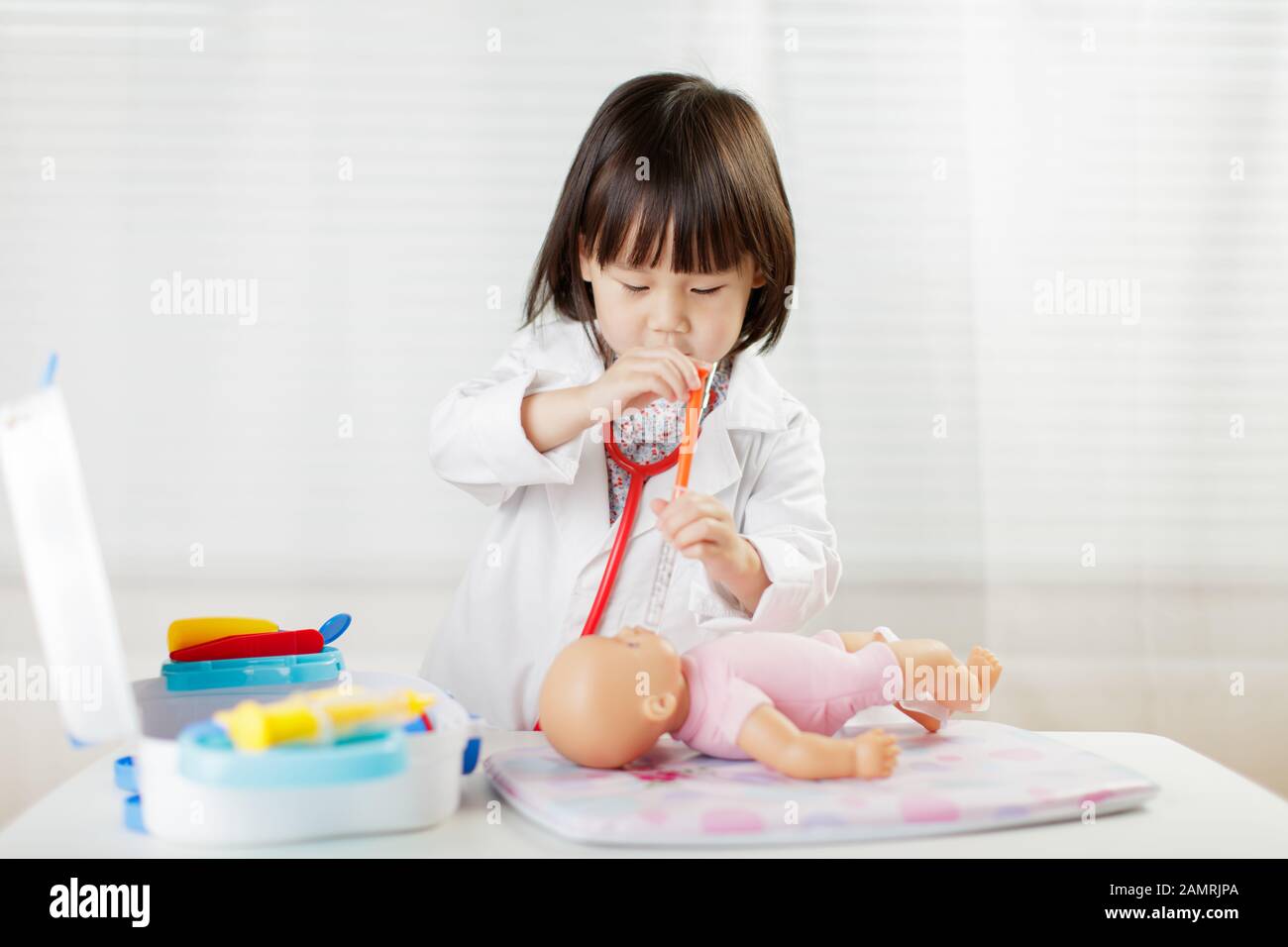 toddler girl pretend play doctor role at home against white background ...