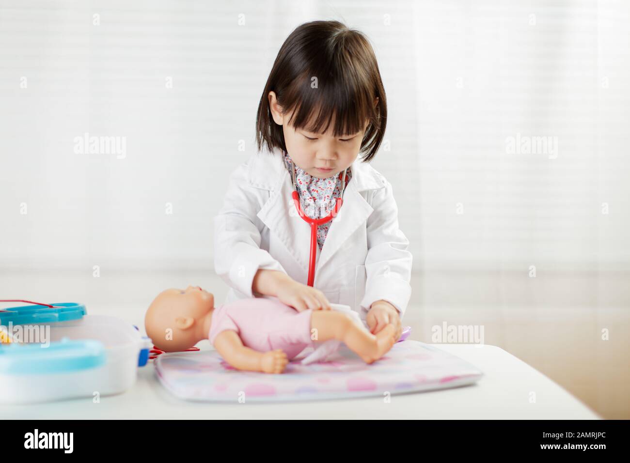 toddler girl pretend play doctor role at home against white background ...