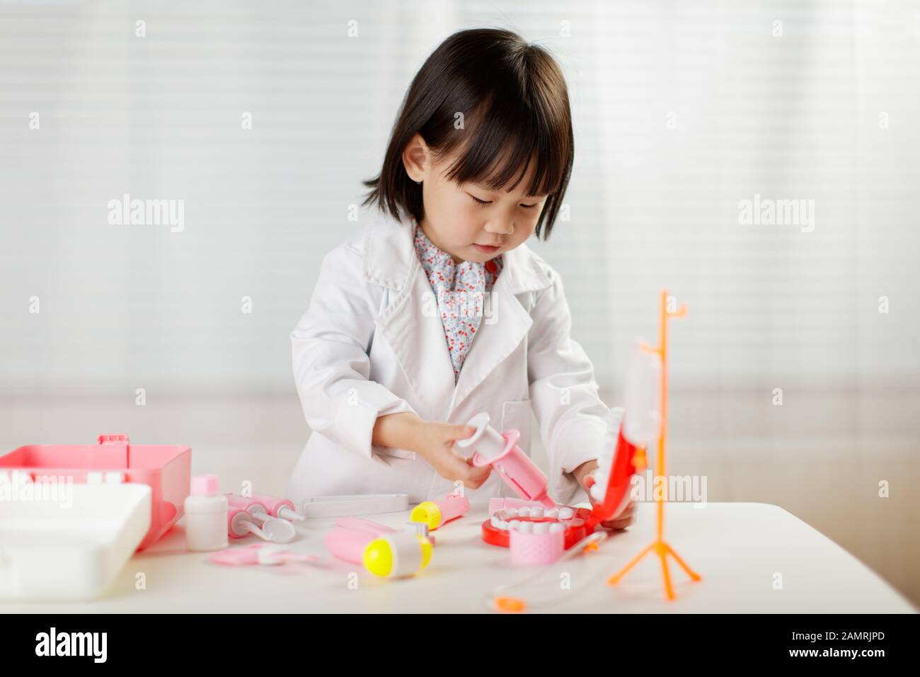 toddler girl pretend play doctor role at home against white background ...