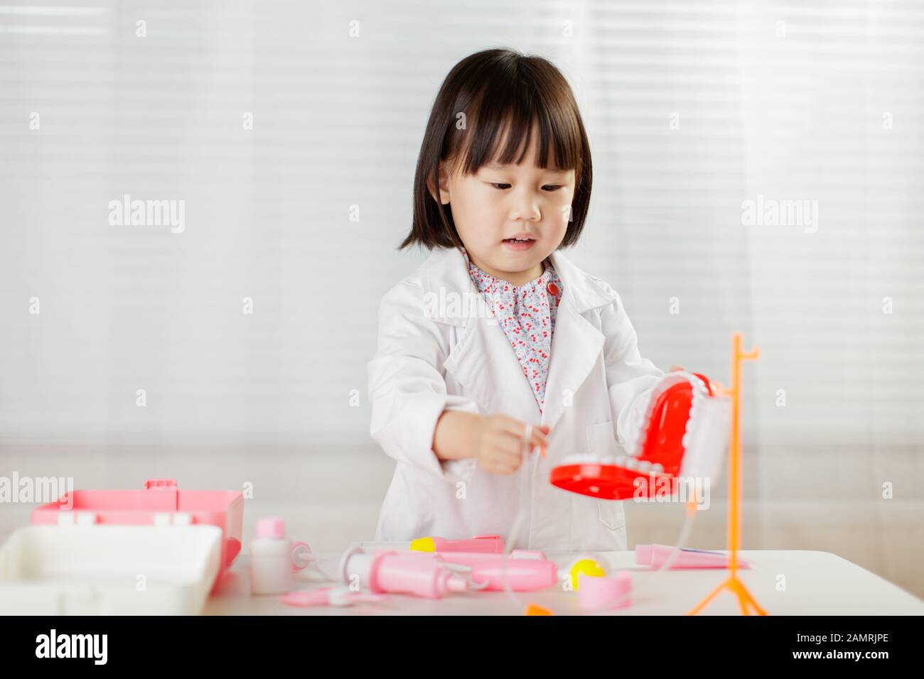 toddler girl pretend play doctor role at home against white background ...