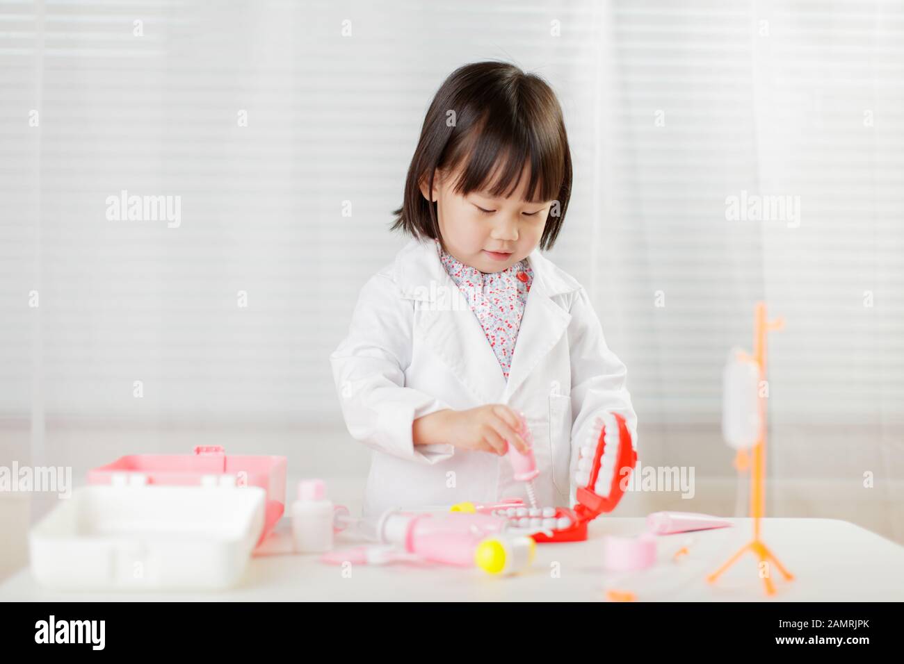toddler girl pretend play doctor role at home against white background ...