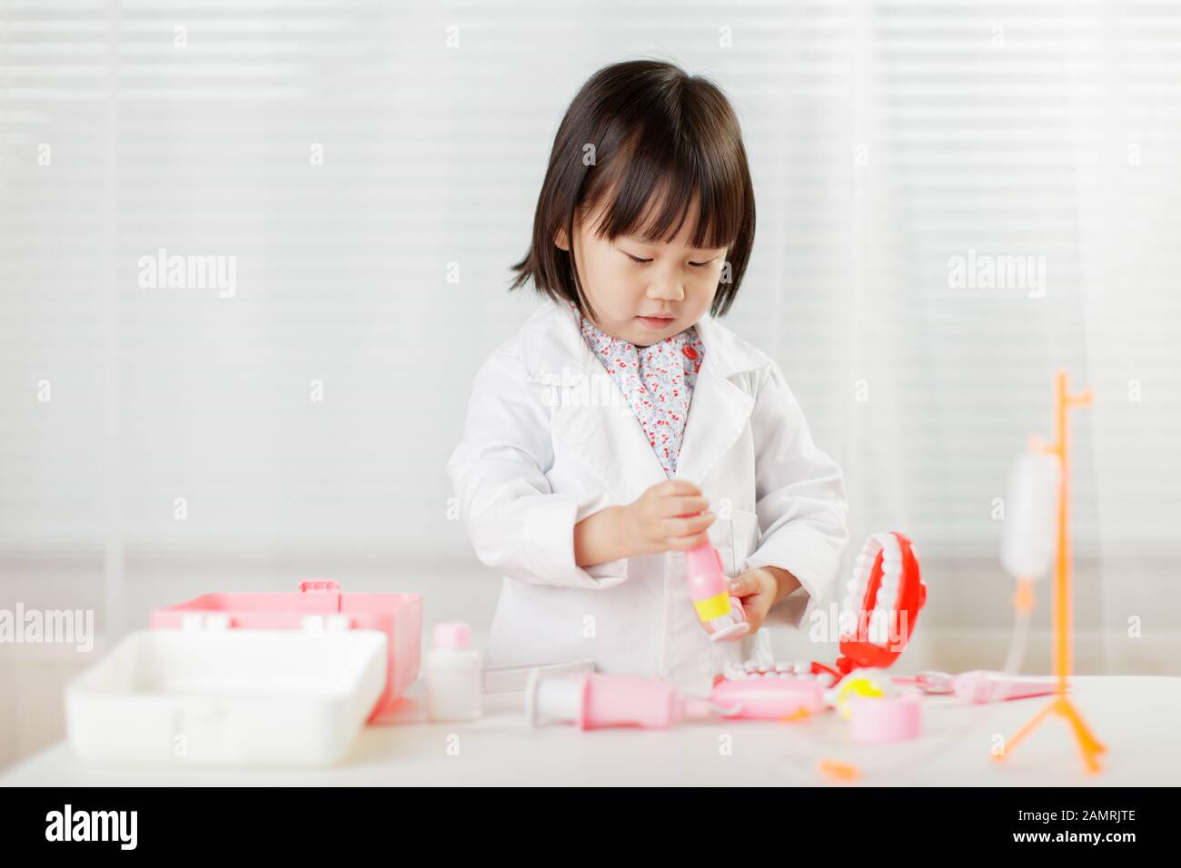 toddler girl pretend play doctor role at home against white background ...