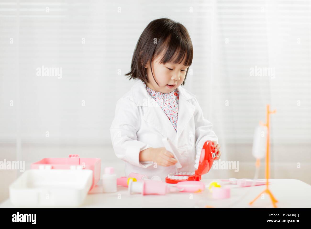toddler girl pretend play doctor role at home against white background ...