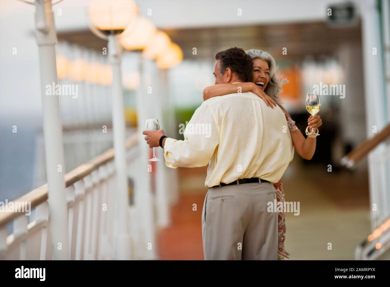 Beautiful woman laughs as she hugs a man as they stand on a pier ...