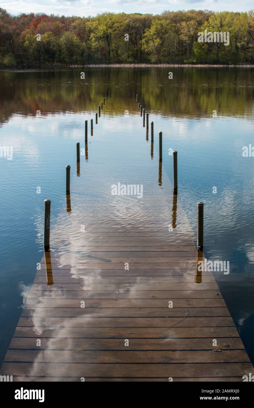 Dock underwater due to flooding, with reflected clouds with trees and ...