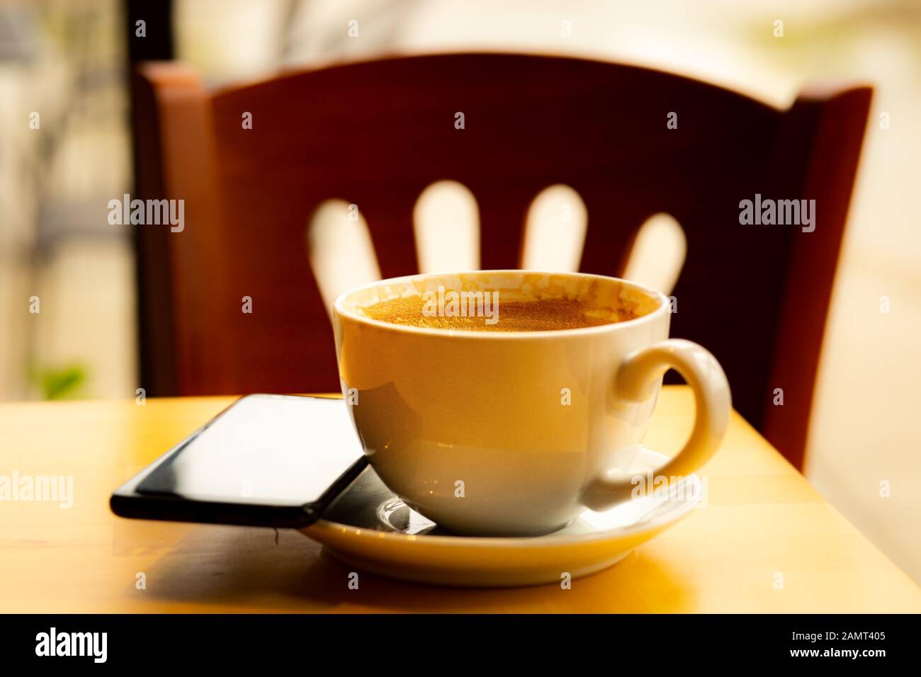Coffee cup and mobile phone on a table in a coffee shop Stock Photo - Alamy