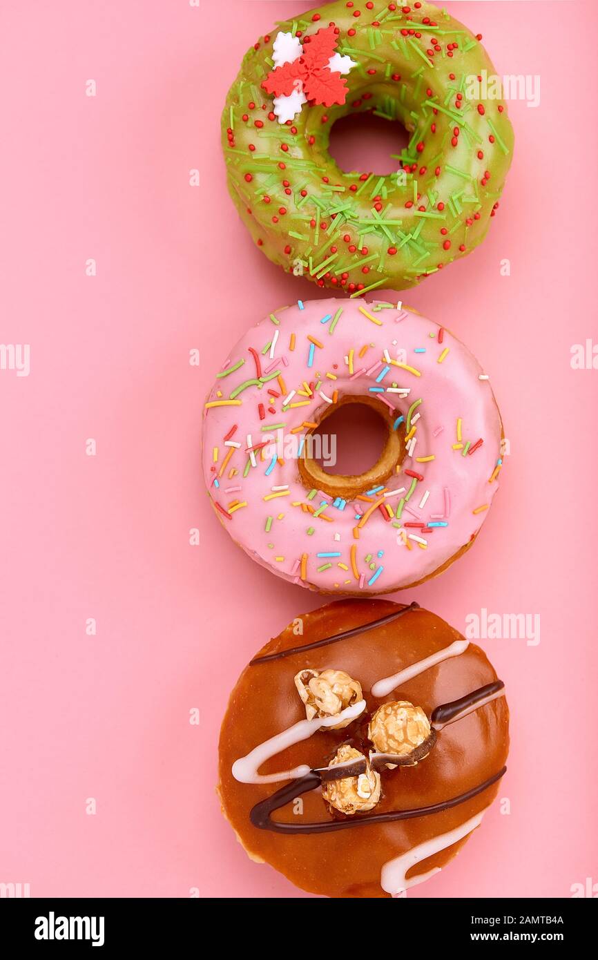 Multi-colored donuts on a pink background folded into a geometric shape ...