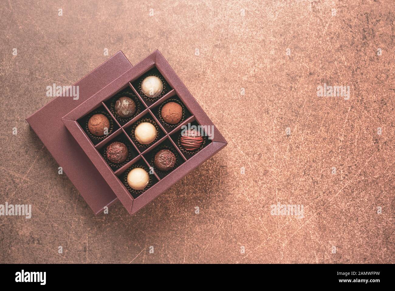 Handmade candies in a brown box on a dark background. Flat top view ...