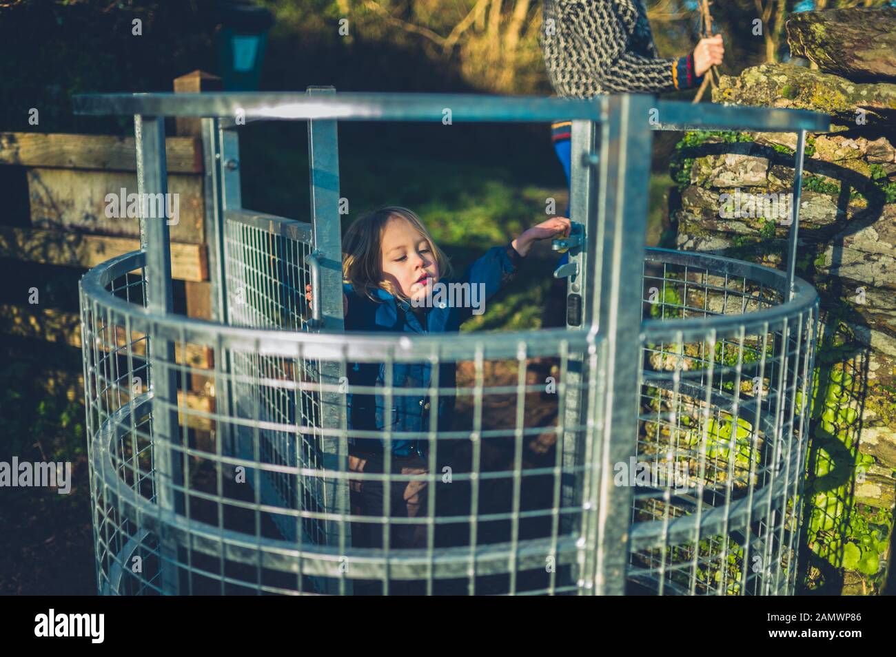 A little toddler is standing in a turnstile gate at sunset Stock Photo ...