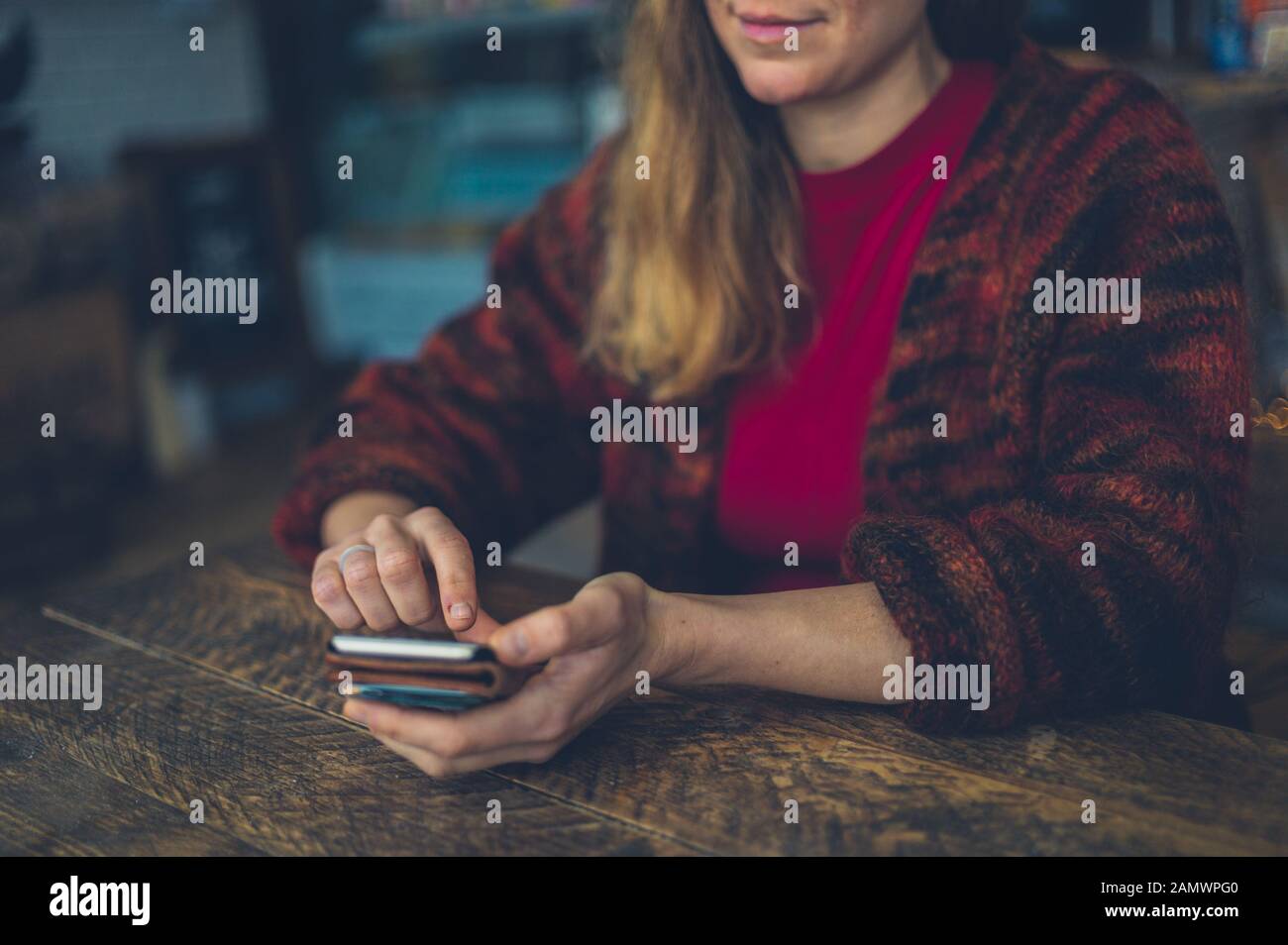A young woman is using a smartphone at a table in a cafe Stock Photo ...