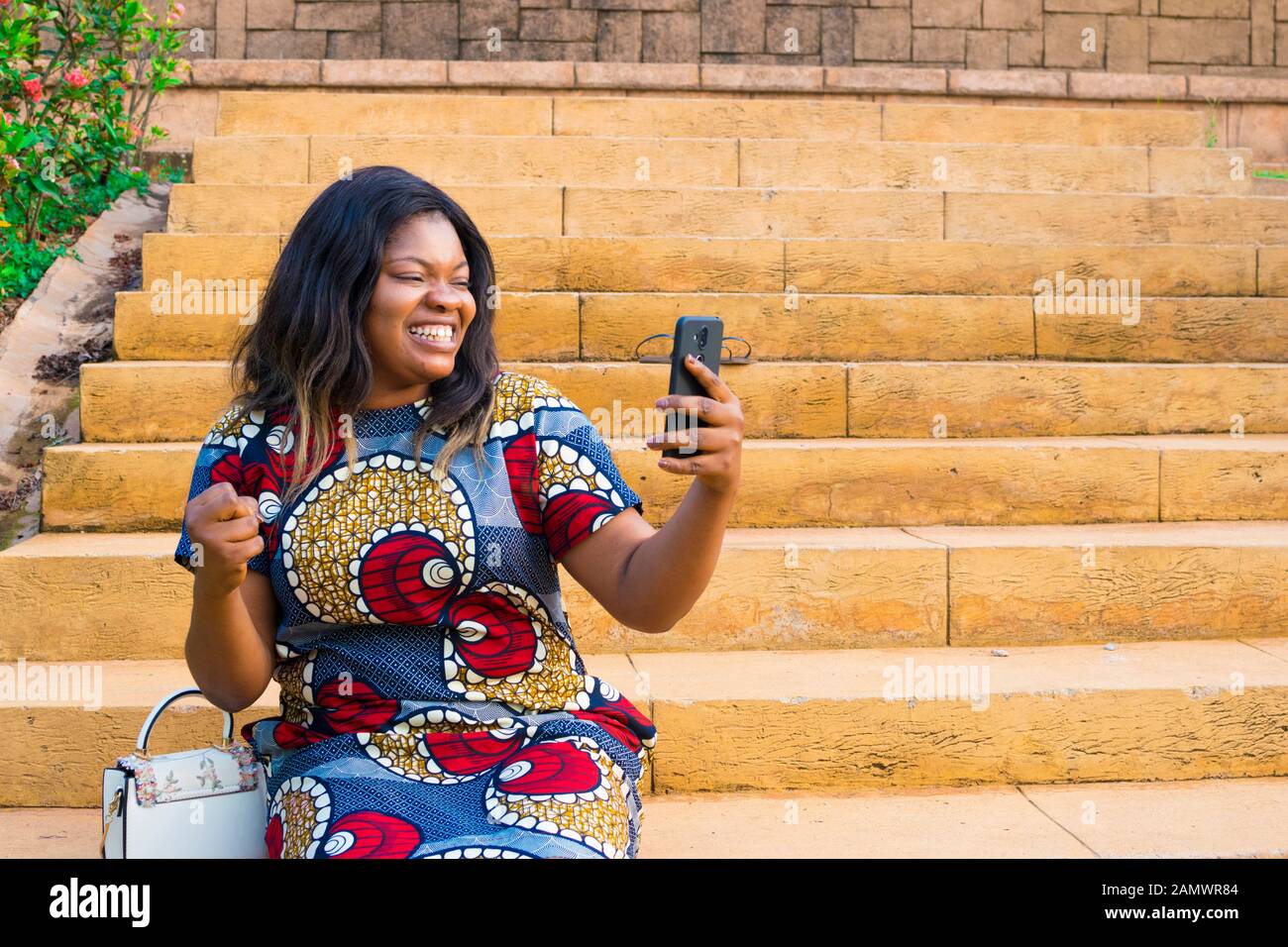 young african woman viewing something on her phone, feeling excited ...