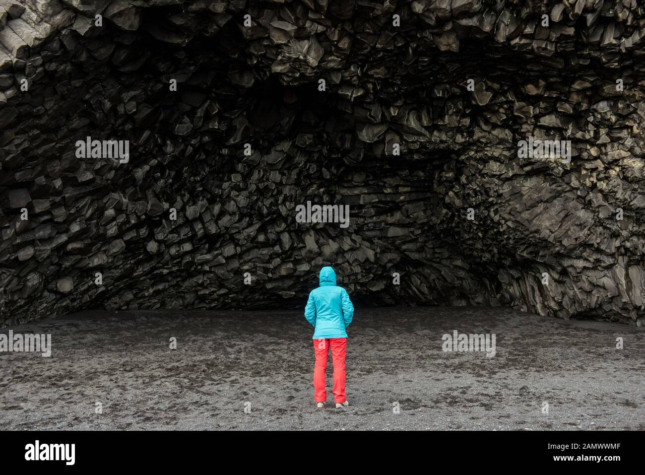 Tourist woman admiring the Halsanefshellir cave formed in black basalt ...