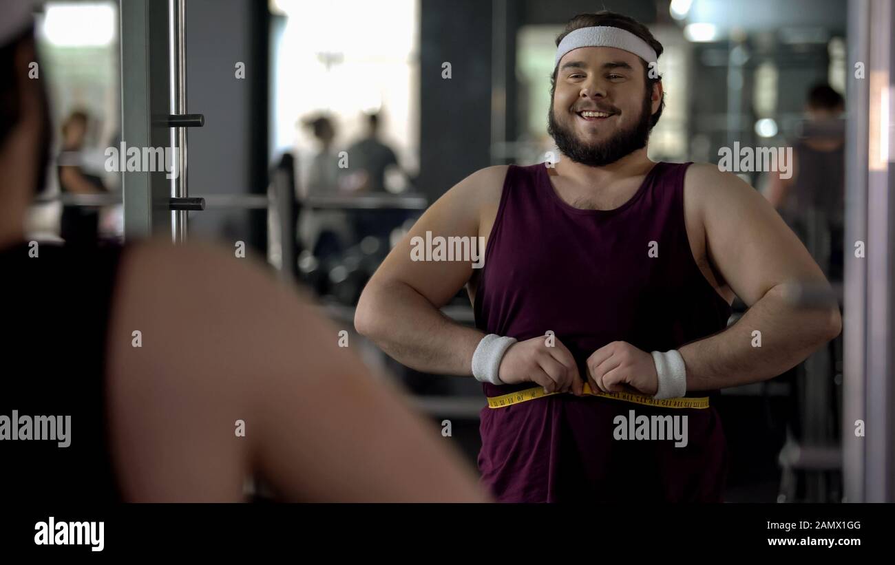Happy obese man measuring fat waist, satisfied with results of training ...