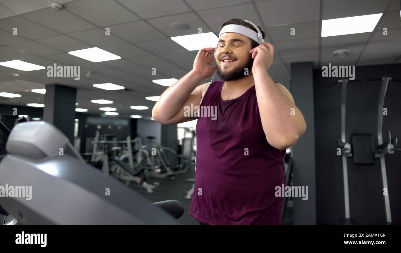Fat man putting on headset and listening to music during jogging on ...