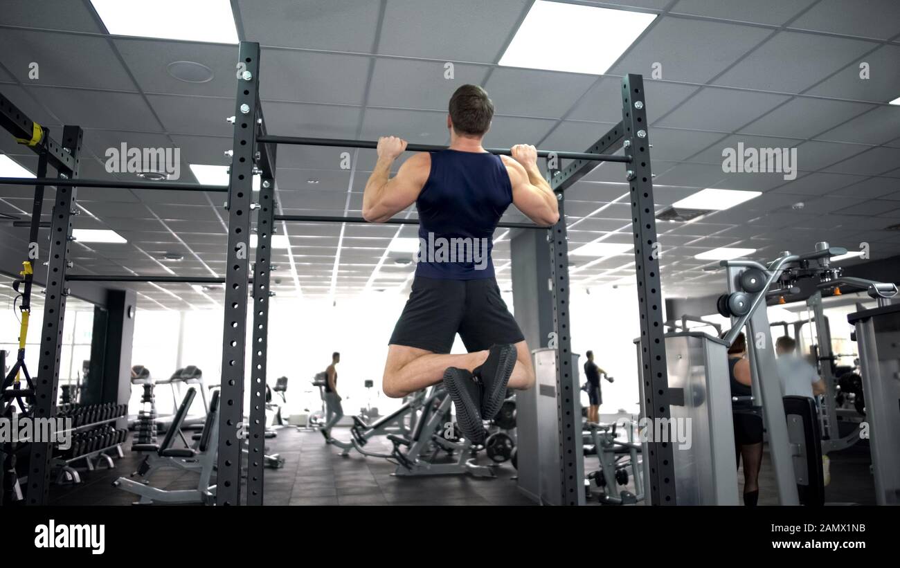 Active man doing pull ups in gym, body workout program, strong muscles ...