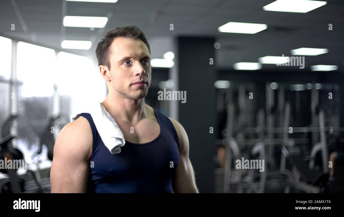 Tired bodybuilder with towel on shoulder relaxing after hard workout in ...