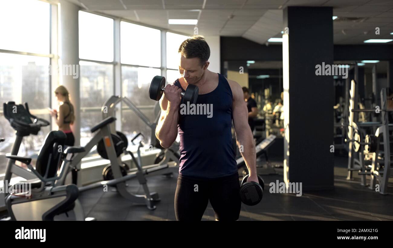 Muscular bodybuilder lifting weight, doing dumbbell curls, workout in ...