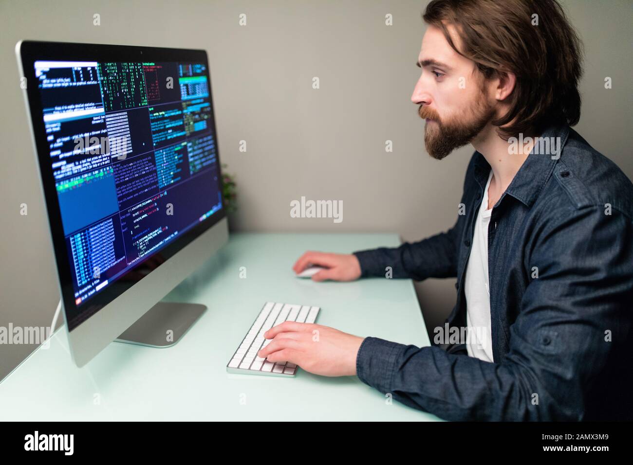 Male programmer working on desktop computer at white desk in office ...
