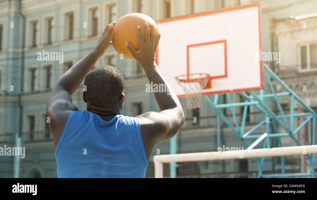 Skilled Afro-American person throwing ball into basket, active sports ...