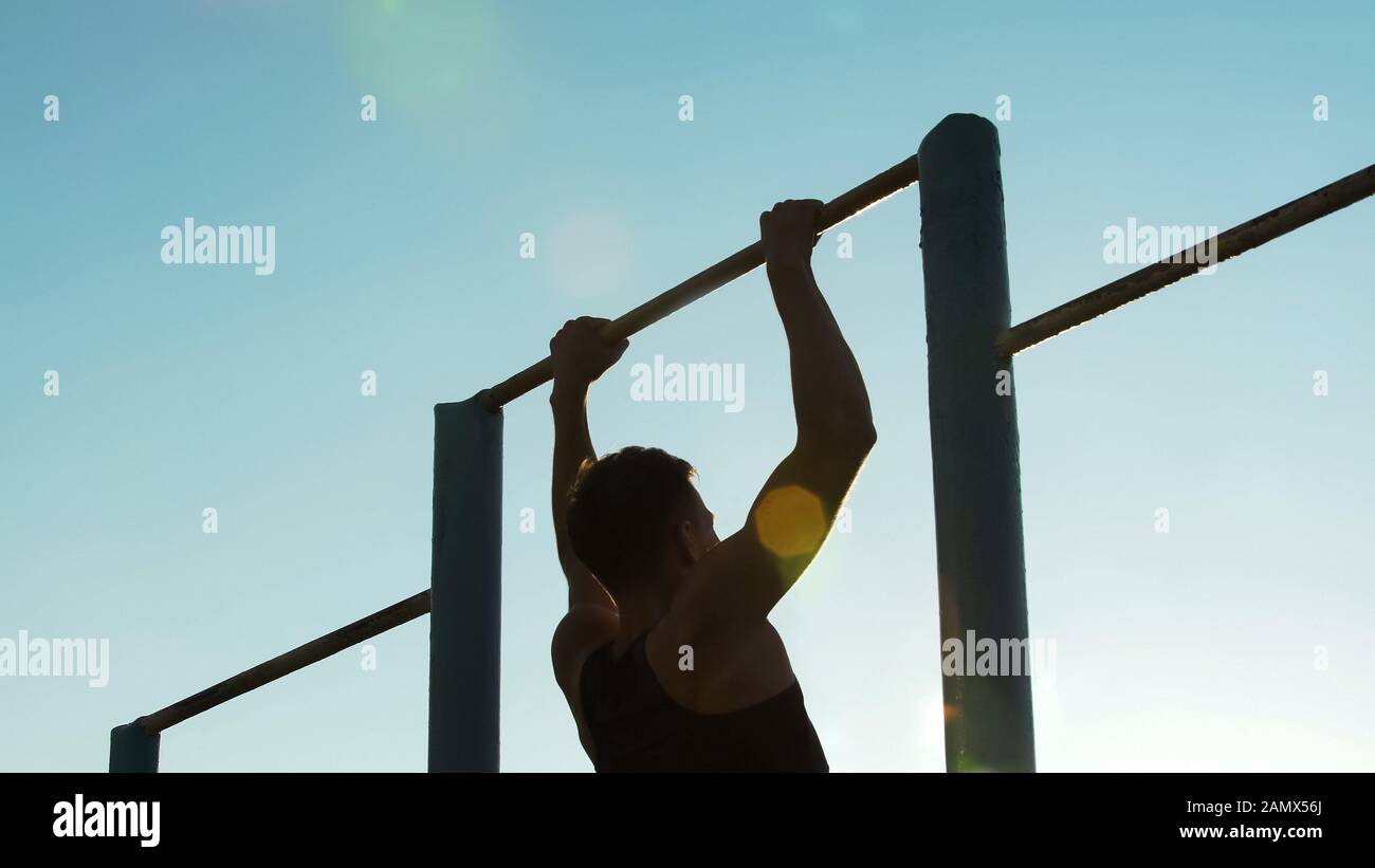 Man athlete training on chin-up bars outdoors, physical strength and ...