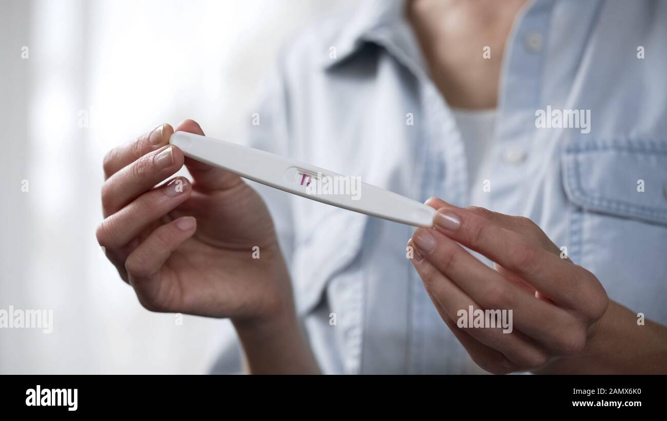 Female holding positive pregnancy test in hands, demonstrating it ...