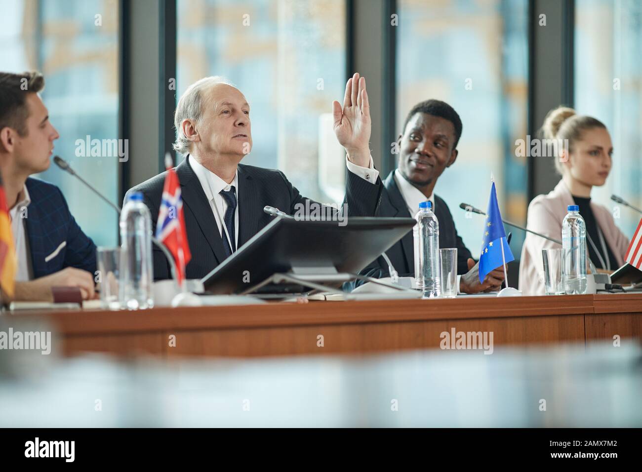 Senior political leader in suit raising his hand he is going to answer ...
