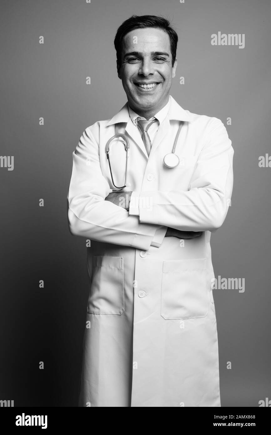 Handsome Persian man doctor against gray background Stock Photo - Alamy