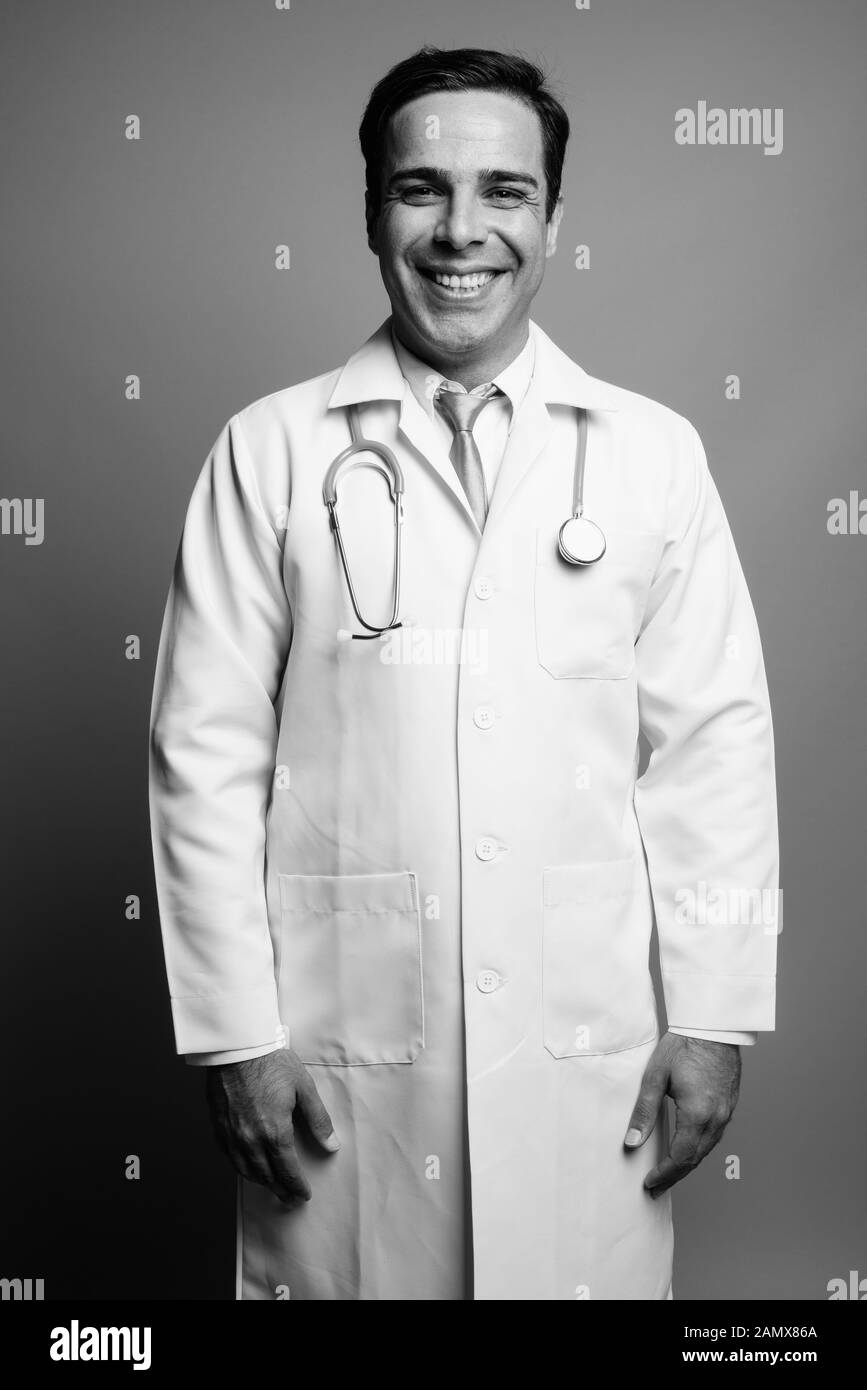 Handsome Persian man doctor against gray background Stock Photo - Alamy