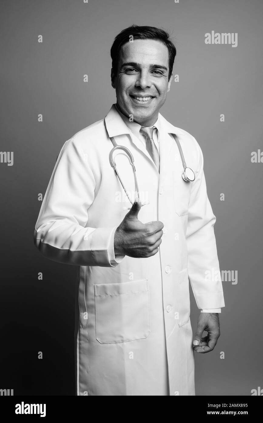 Handsome Persian man doctor against gray background Stock Photo - Alamy