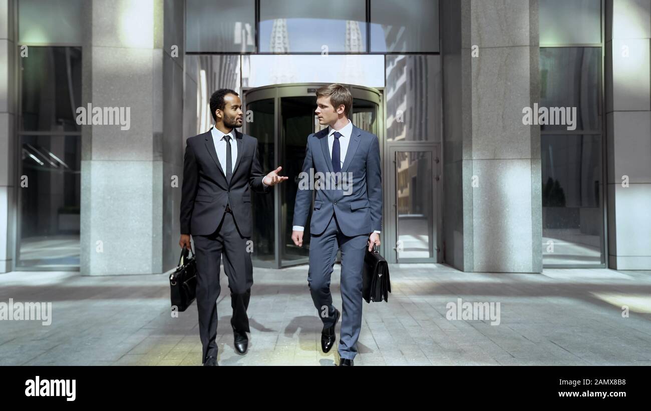 Coworkers going out office center, discussing joint project, end of ...