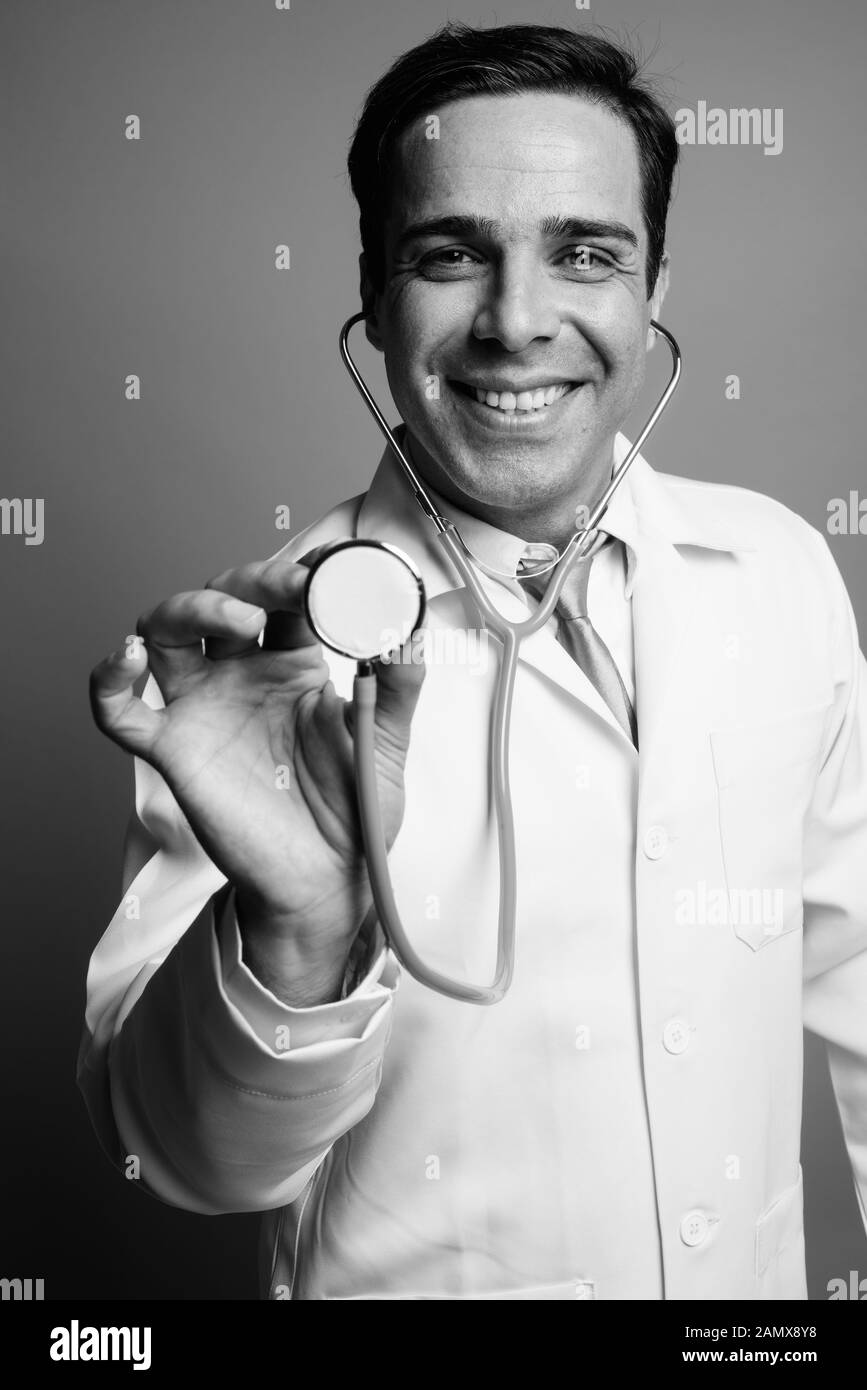 Handsome Persian man doctor against gray background Stock Photo - Alamy